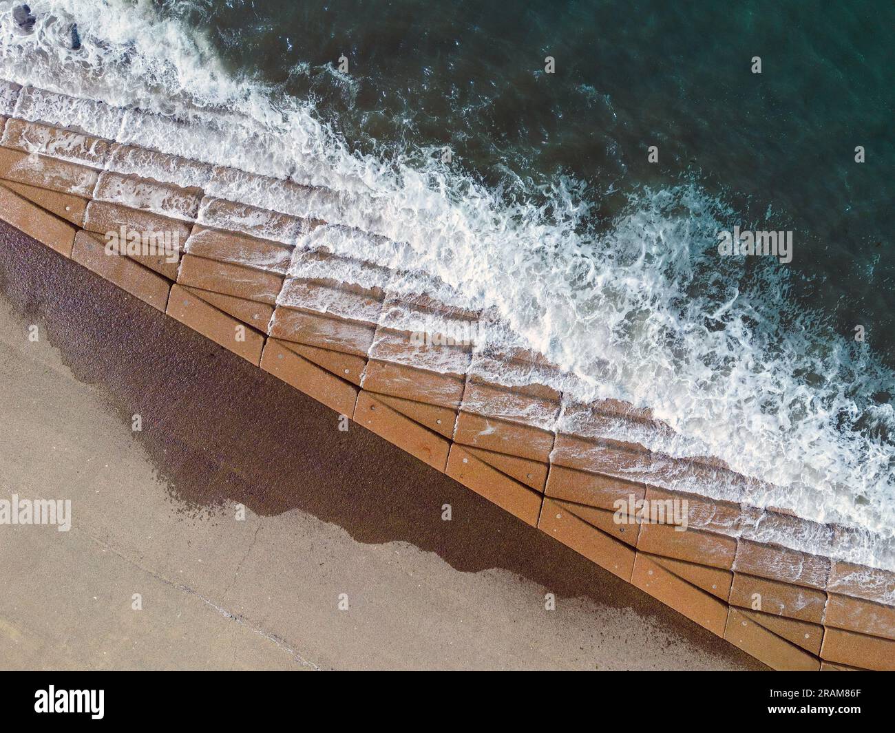 Aerial view of waves breaking over the concrete steps of a promenade at ...