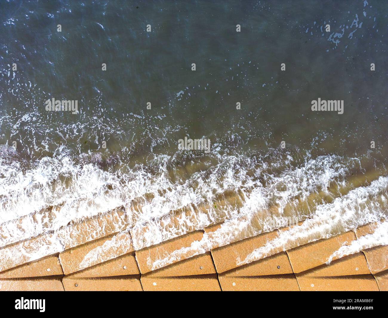 Aerial view of waves breaking over the concrete steps of a promenade at ...