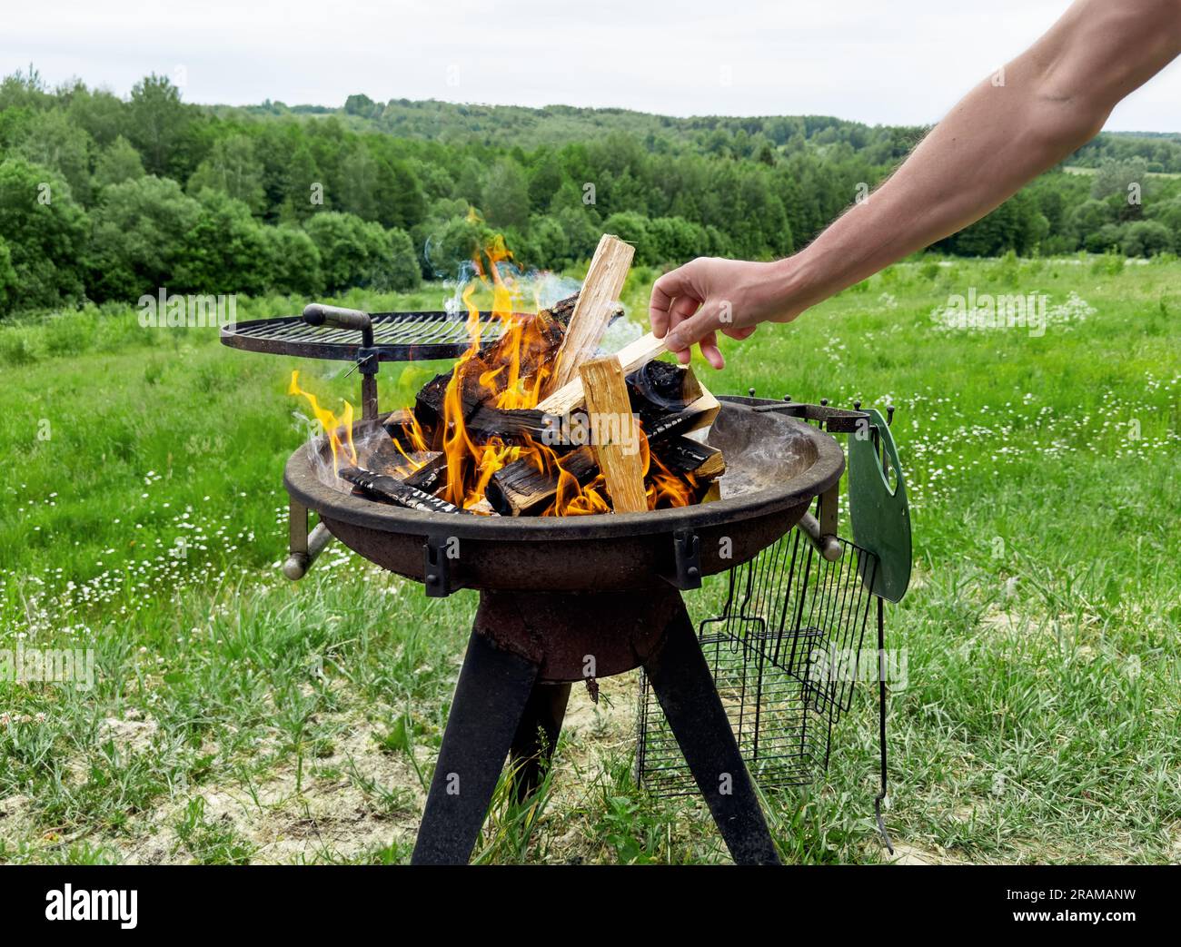 BBQ grill with fire over summer nature. Hand preparing barbecue machine ...