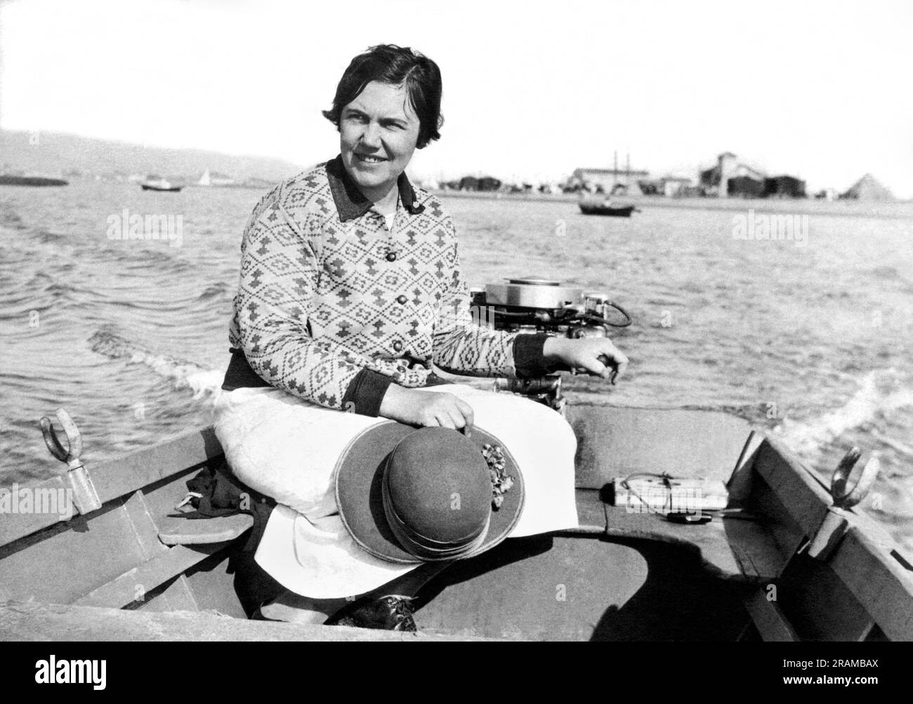 United States: C. 1925. A woman in a small boat with an early model ...