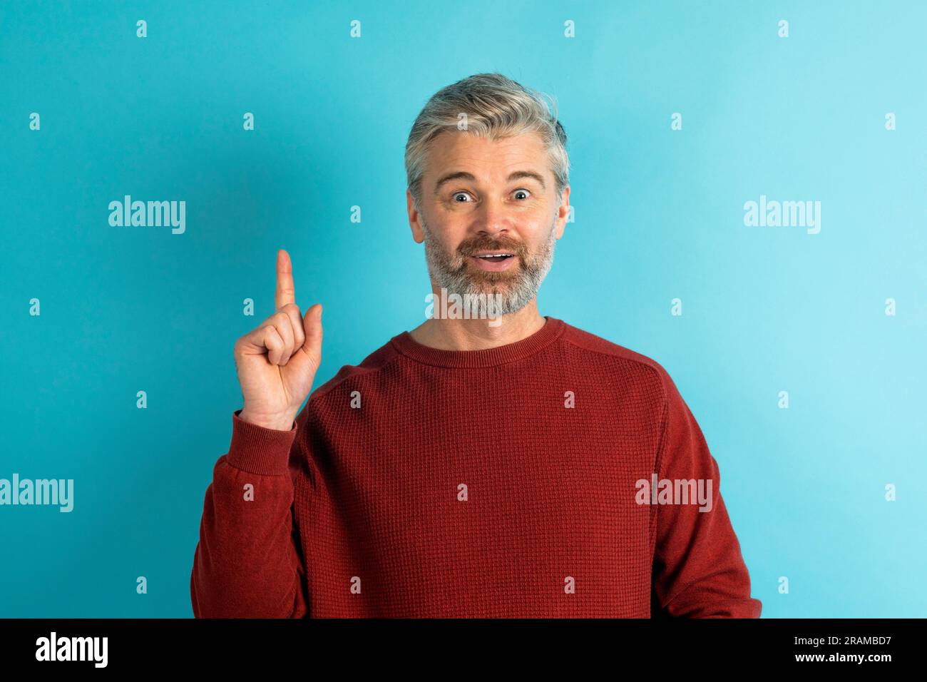 Excited inspired middle aged man raising finger up on blue Stock Photo ...