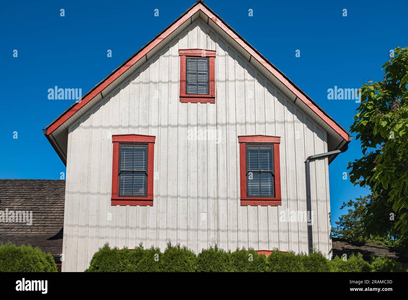 A beautiful white house with red framed shuttered windows. Three ...