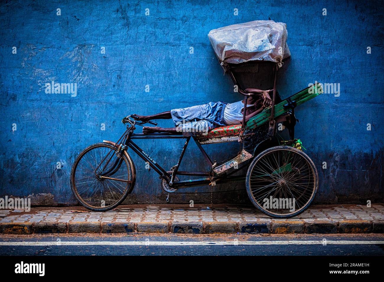 Indian cycle rickshaw driver sleeps on his bicycle in street of New ...