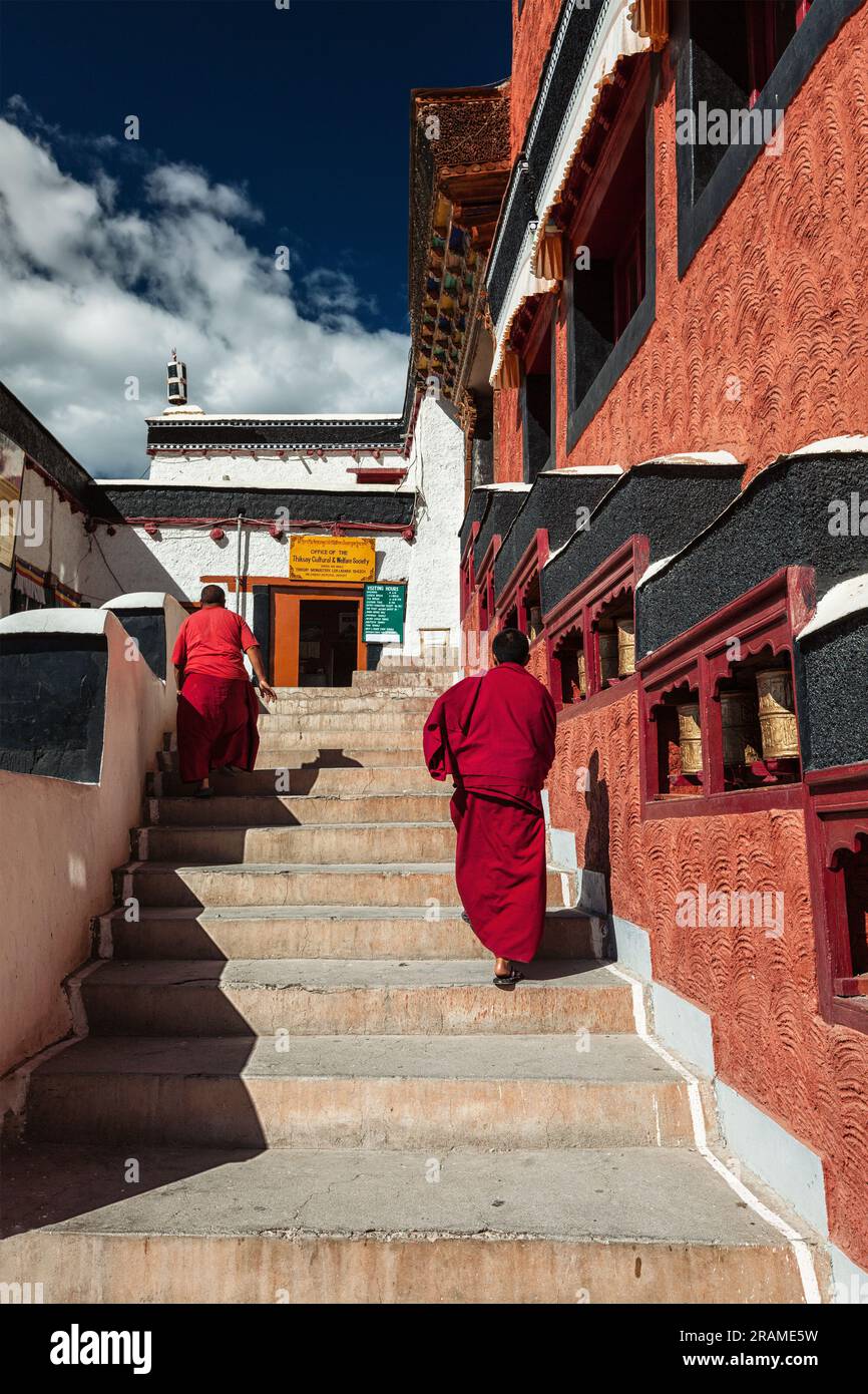 Young Buddhist monks walking on stairs along prayer wheels in Thiksey ...
