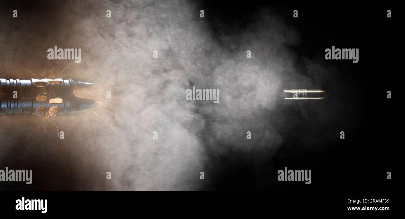 Copper colored bullet just leaving the gun with smoke and sparks flying ...