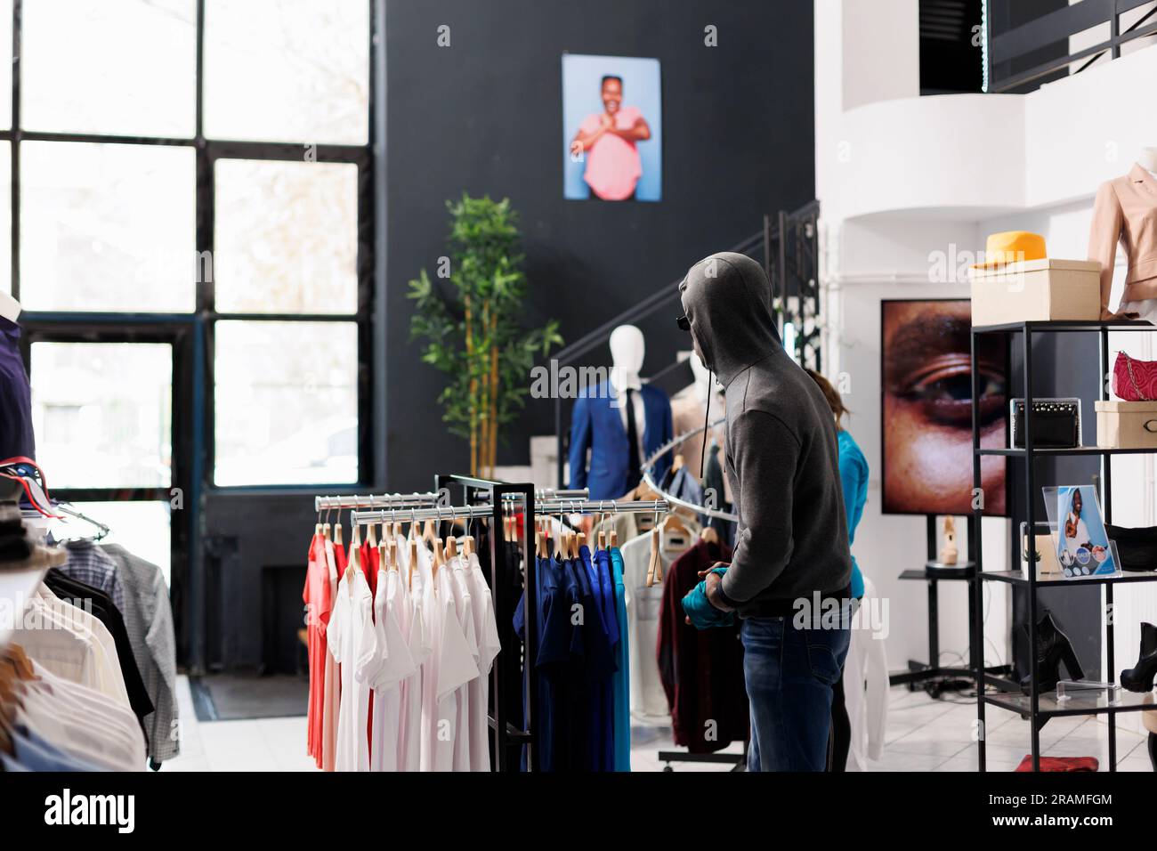 Robber wearing hood and sunglasses, trying to sneak stolen trendy ...