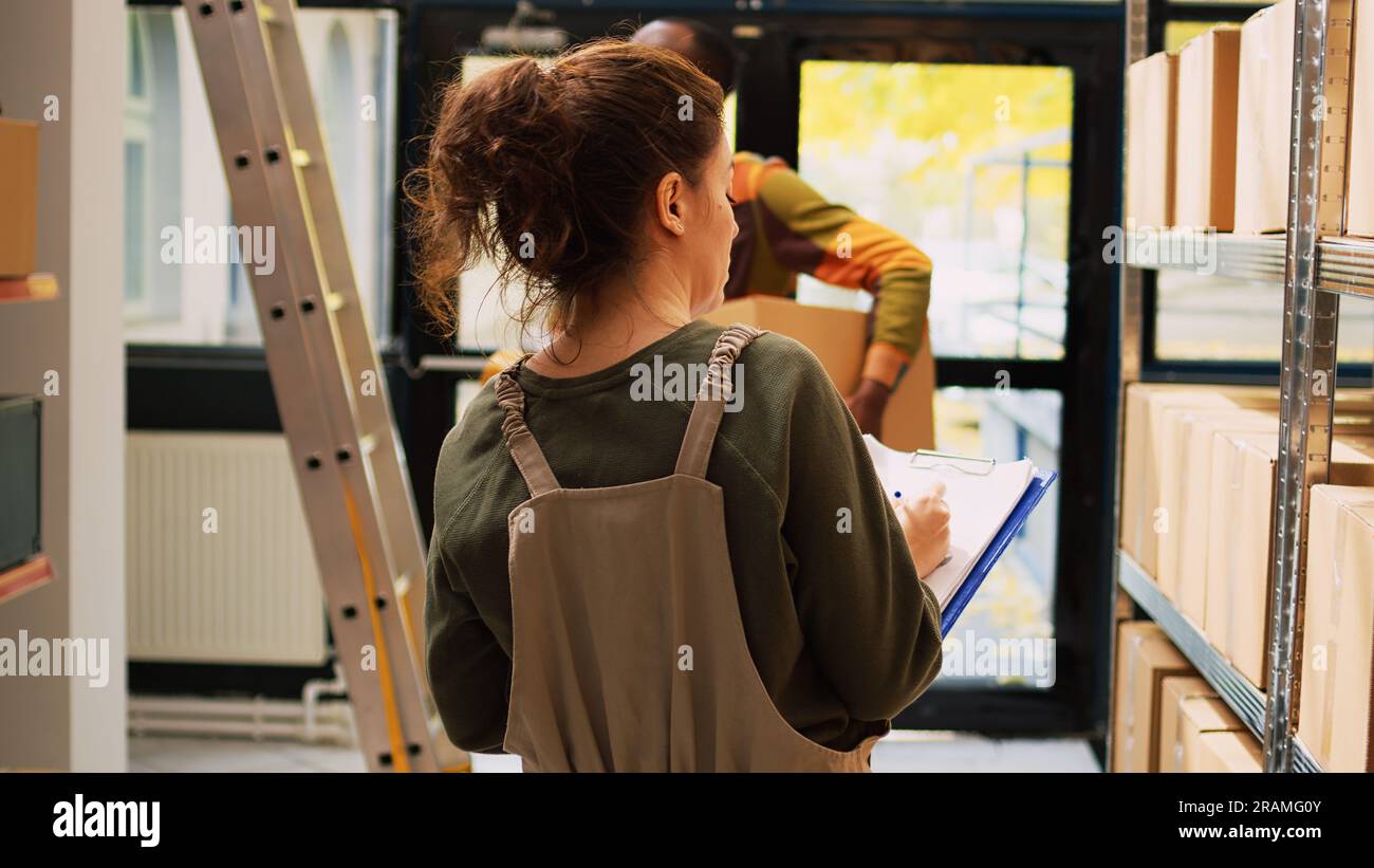 Depot manager verifying products list in storage room, working on ...