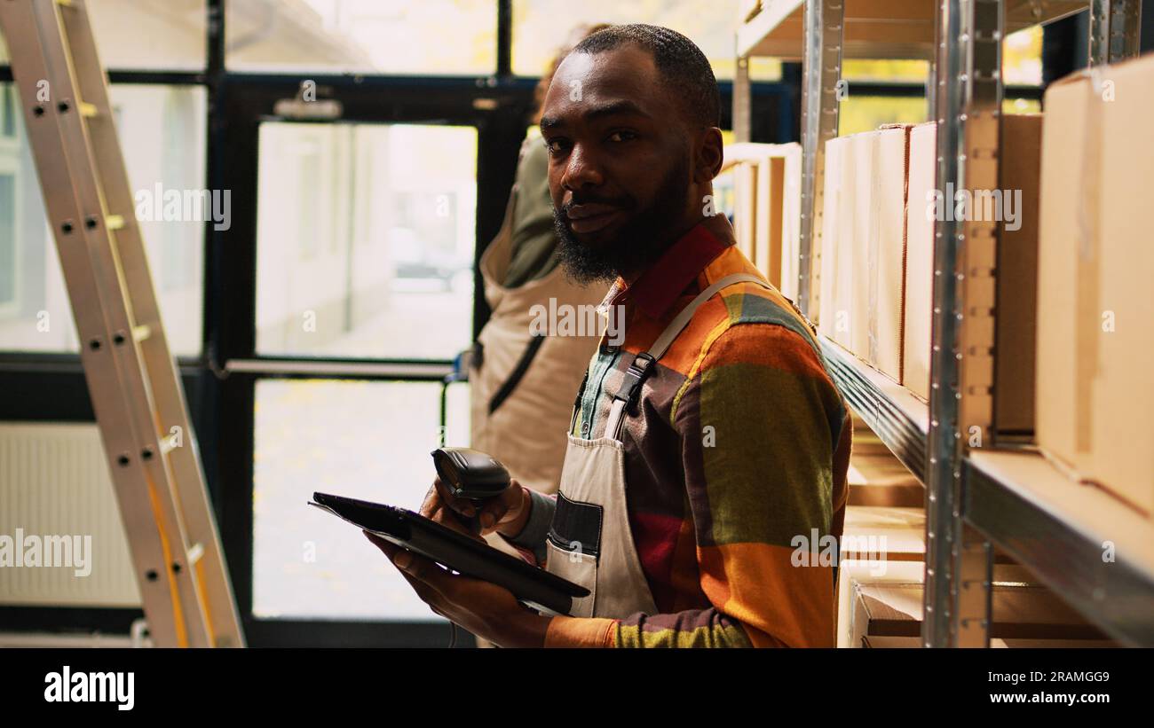 African american man scanning barcodes with tablet, working on quality ...