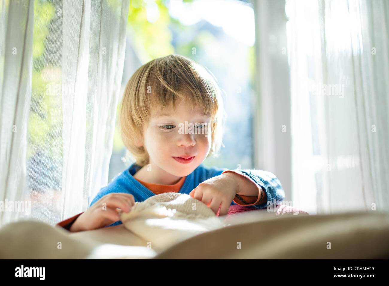 Adorable toddler boy looking through the window at home. Little child ...