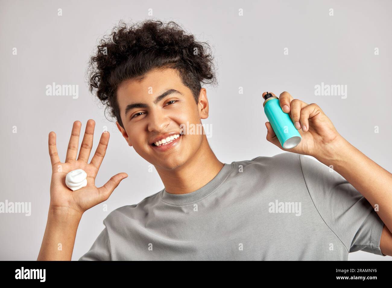 Young guy with black curly hair applies face wash to his hands, ready ...