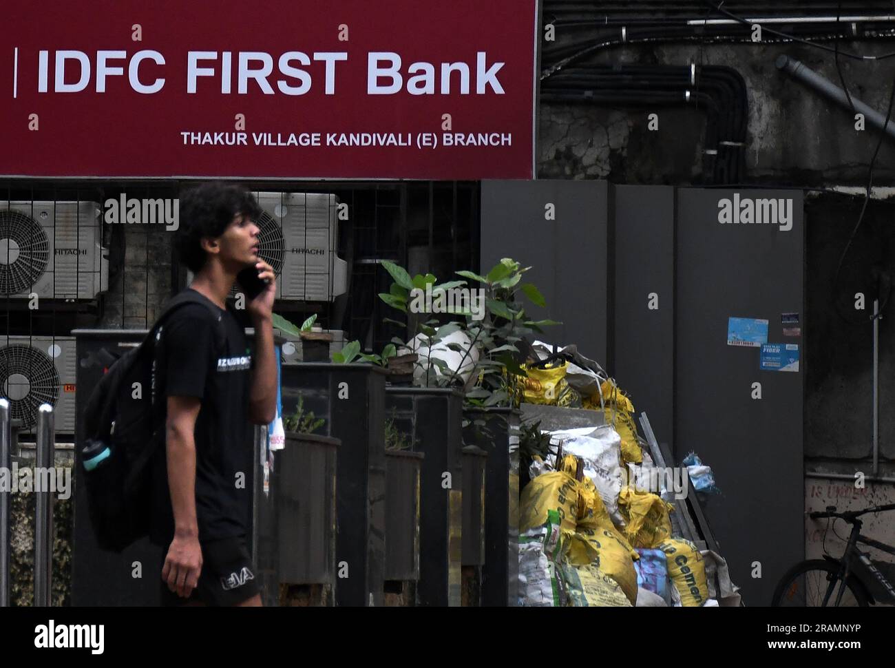 A man talking on phone walks past the IDFC First bank branch in Mumbai ...