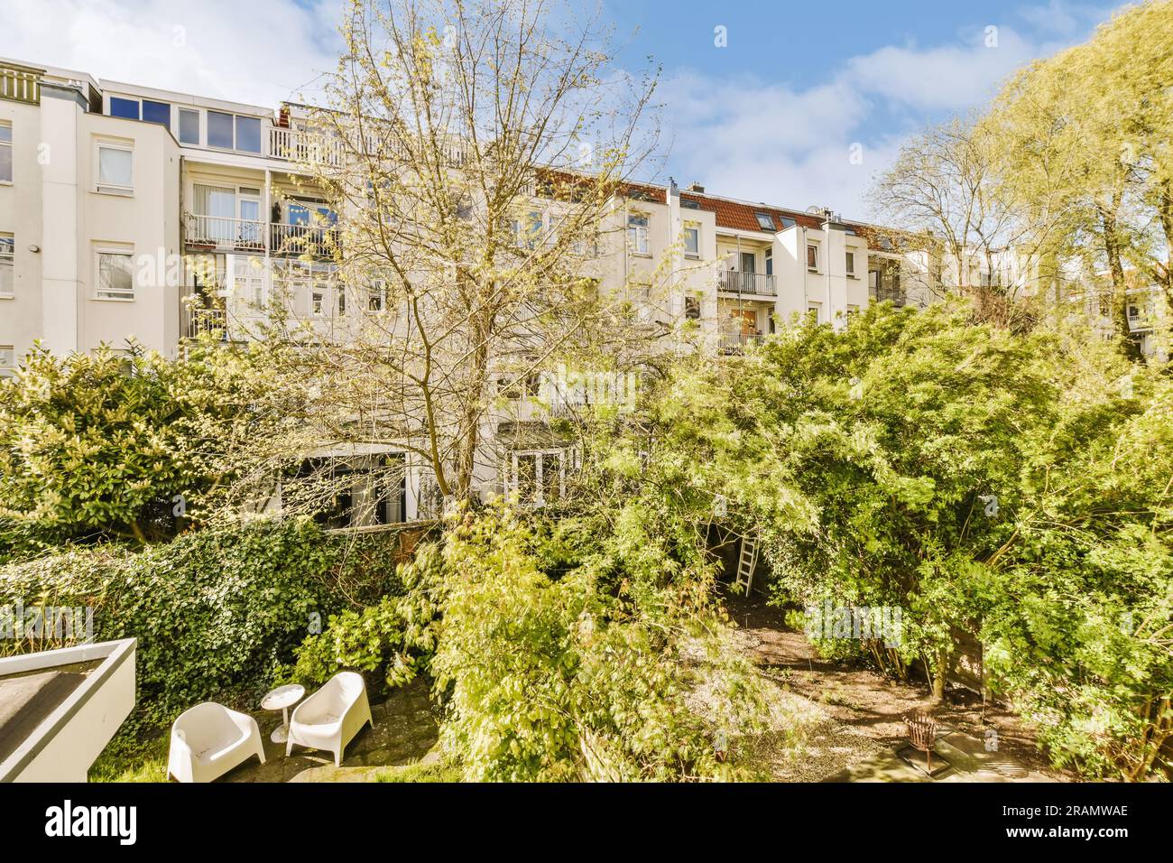 an apartment complex with trees and bushes in the fore - image viatafo ...