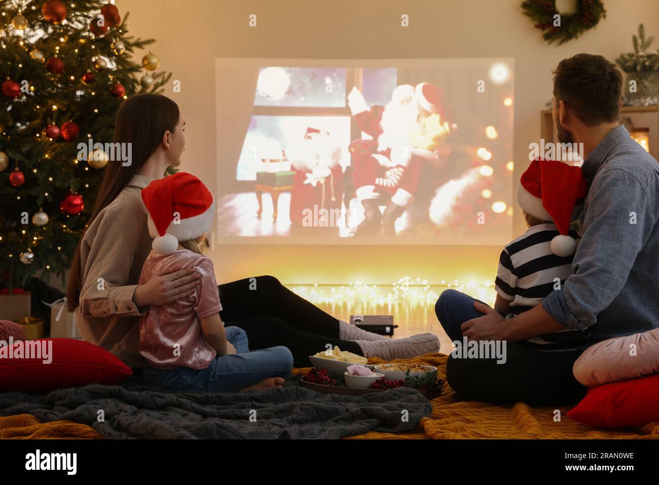 Family watching Christmas movie via video projector in cosy room ...