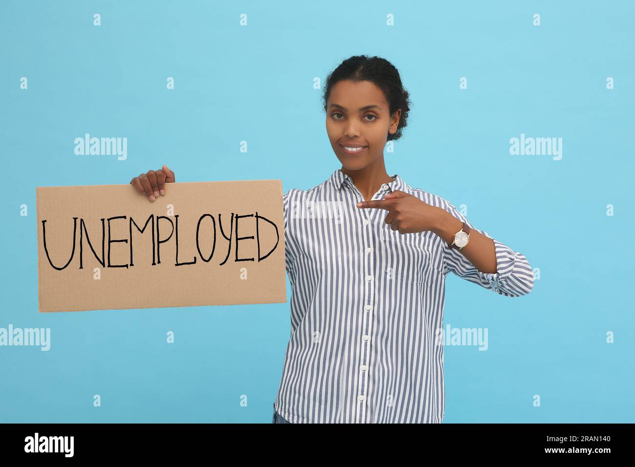 African American woman holding sign with word Unemployed on light blue ...