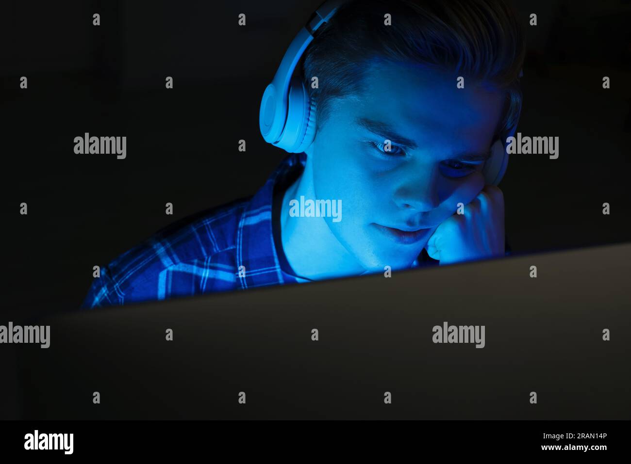 Teenage boy in headphones using computer at night. Internet addiction ...