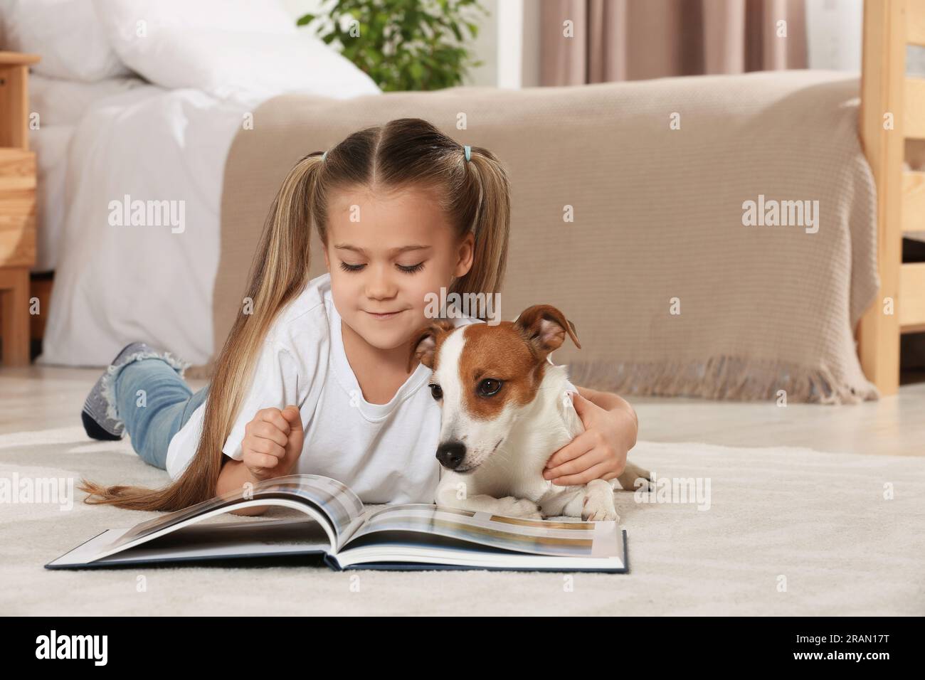Cute girl reading book on floor with her dog at home. Adorable pet ...