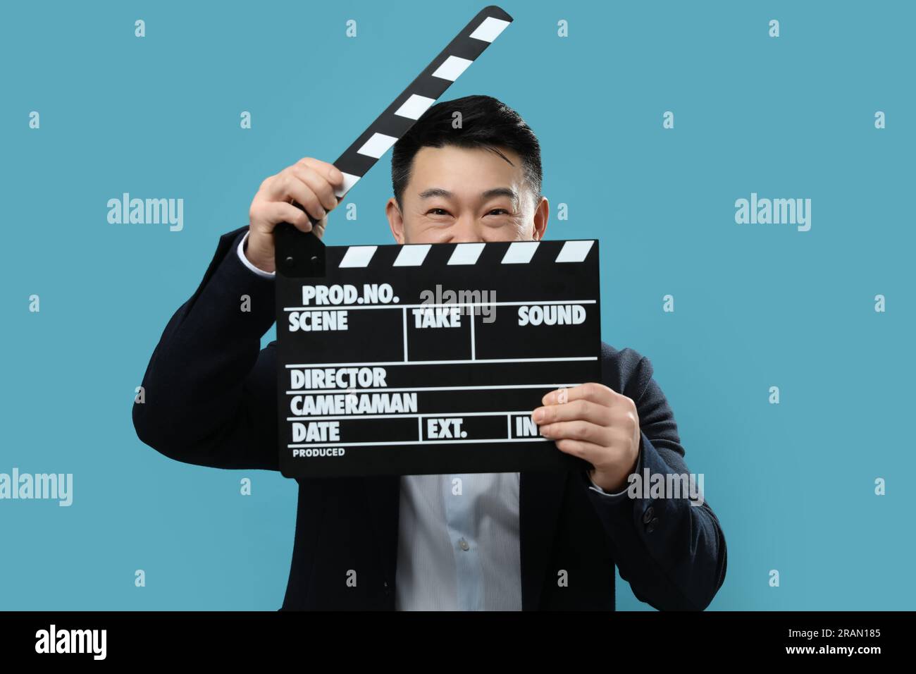 Happy asian actor with clapperboard on light blue background. Film ...
