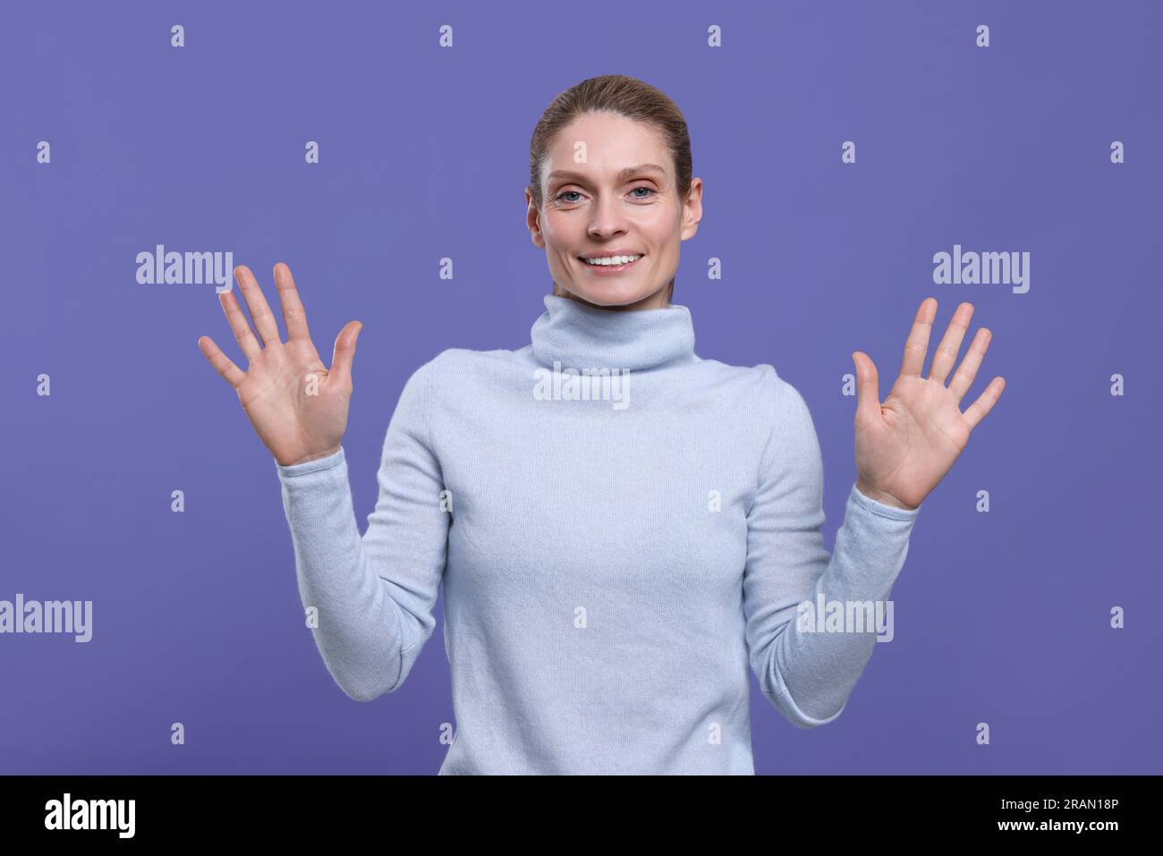 Woman giving high five with both hands on purple background Stock Photo ...