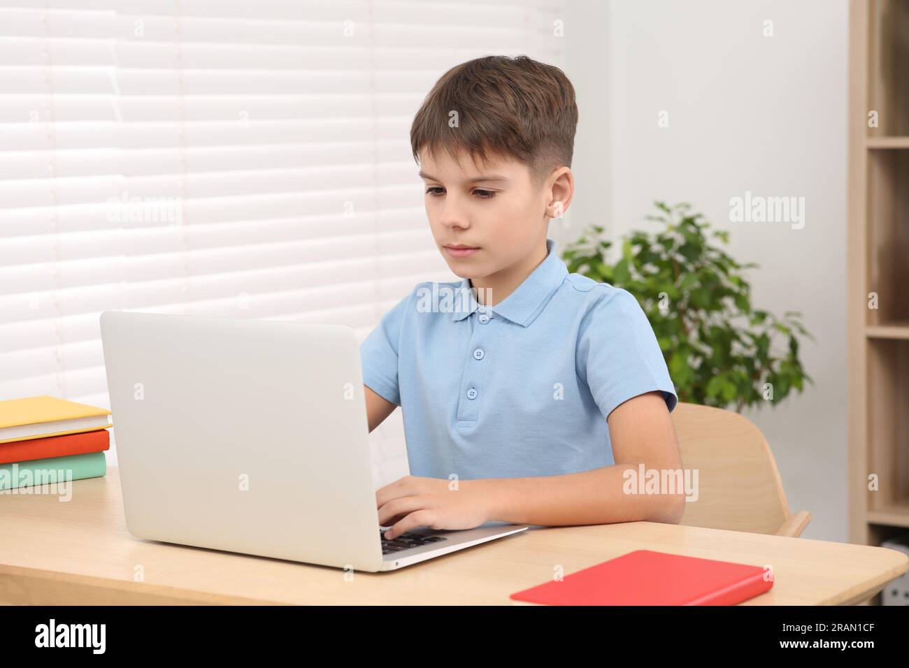 Boy using laptop at desk in room. Home workplace Stock Photo - Alamy