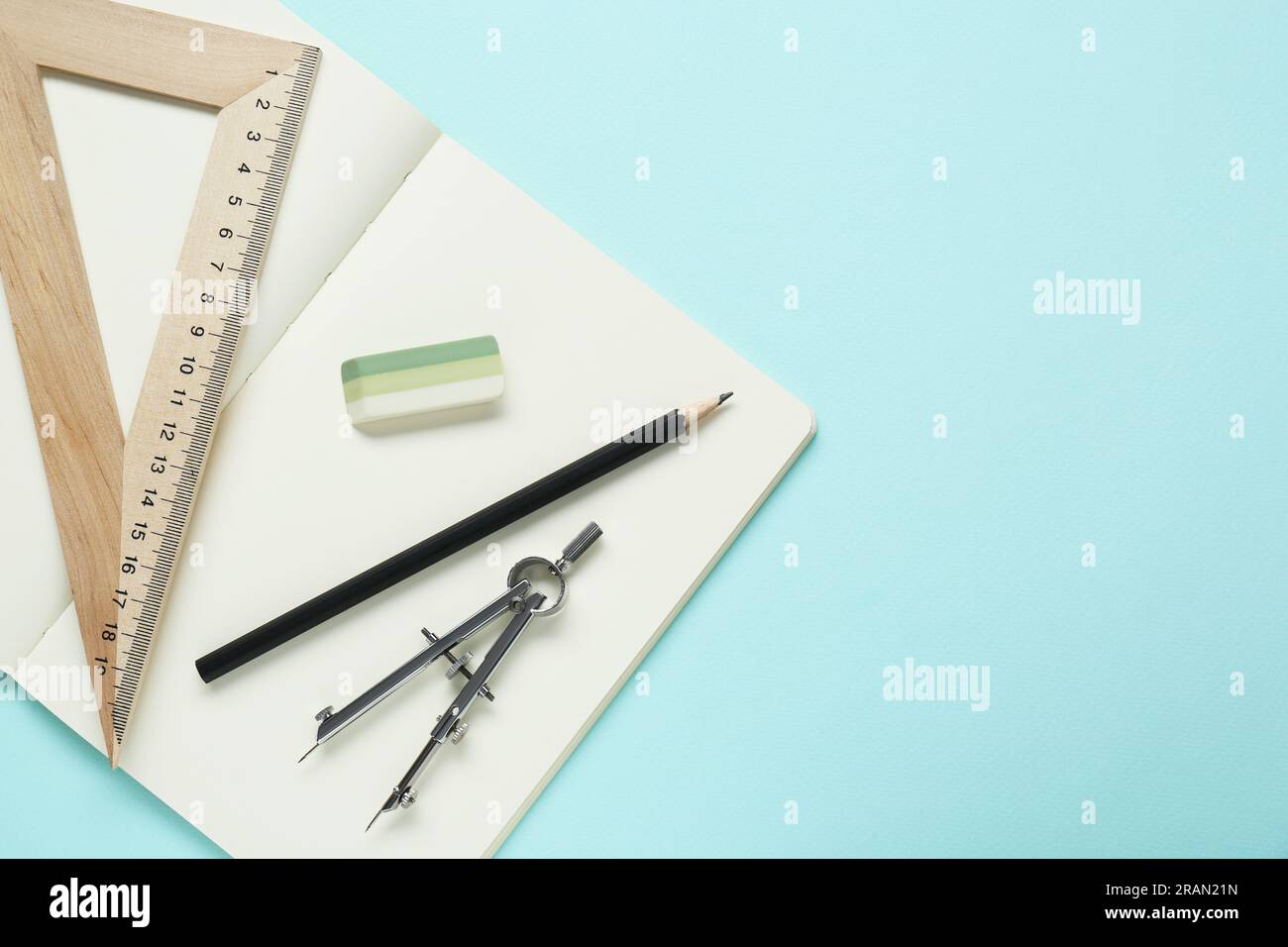 Different rulers, pencil, compass and notebook on turquoise background ...