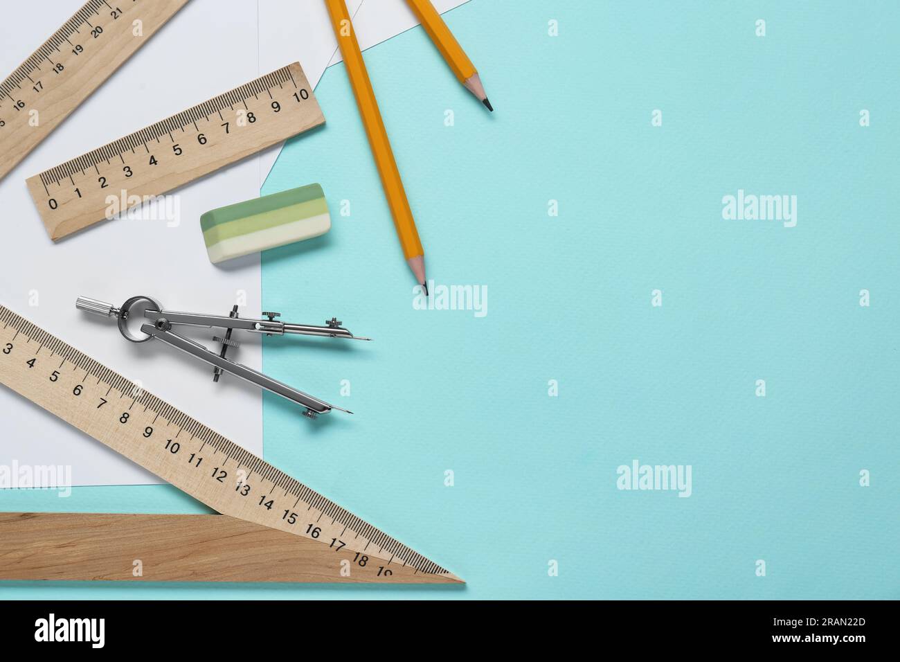 Different rulers and compass on turquoise background. Space for text ...