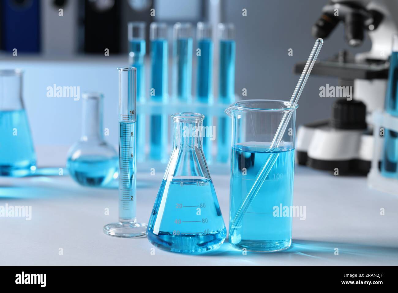 Different laboratory glassware with light blue liquid on table Stock ...