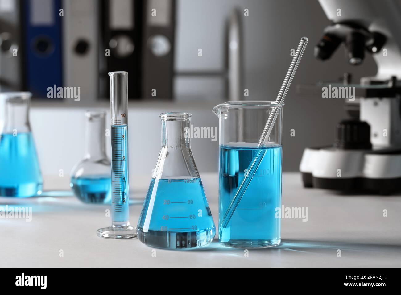 Different laboratory glassware with light blue liquid on table Stock ...