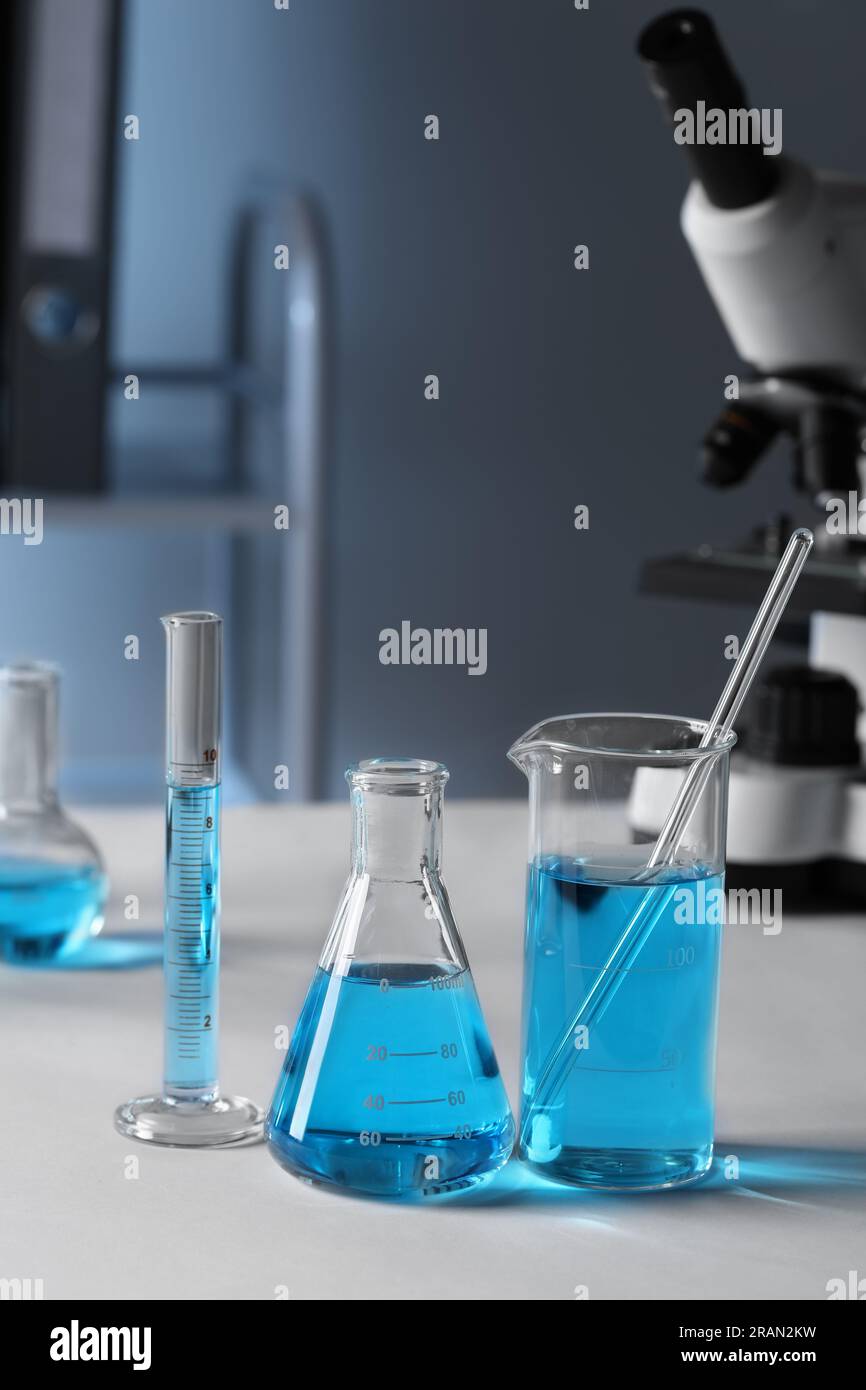 Different laboratory glassware with light blue liquid on table Stock ...