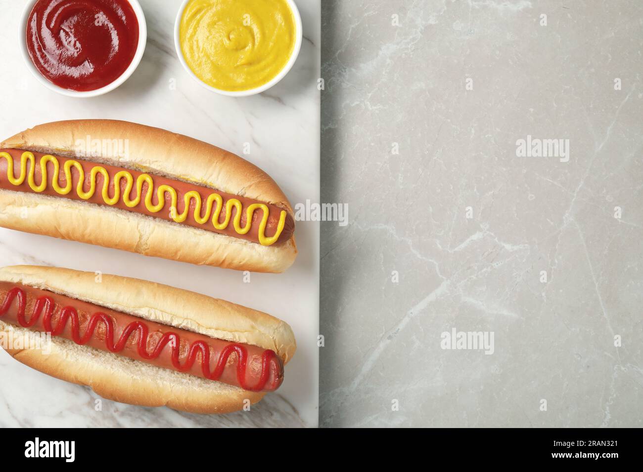 Fresh delicious hot dogs with sauces on light grey marble table, top ...