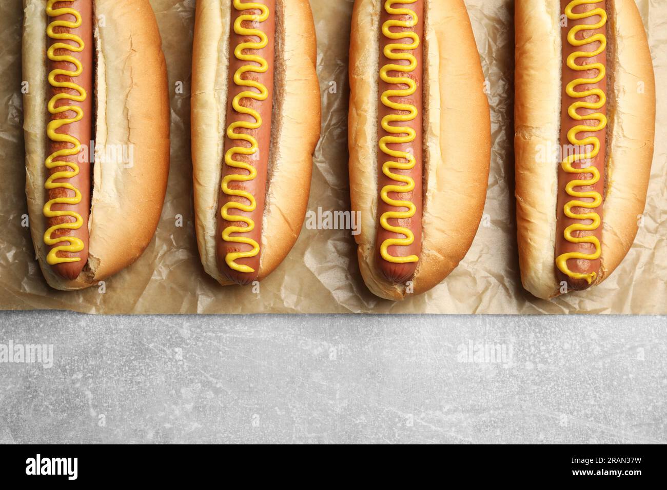 Fresh delicious hot dogs with mustard on light grey table, top view ...