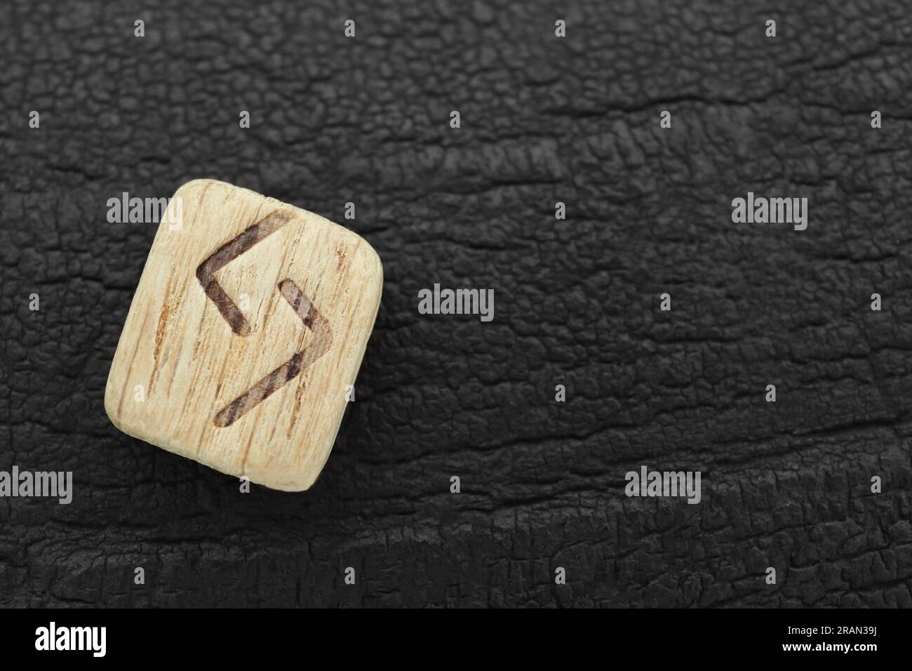 Wooden rune Jera on black textured background, top view. Space for text ...
