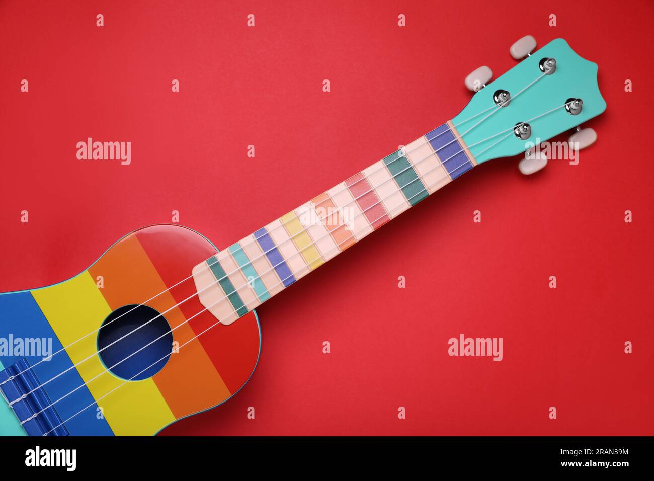 Colorful ukulele on red background, top view. String musical instrument ...