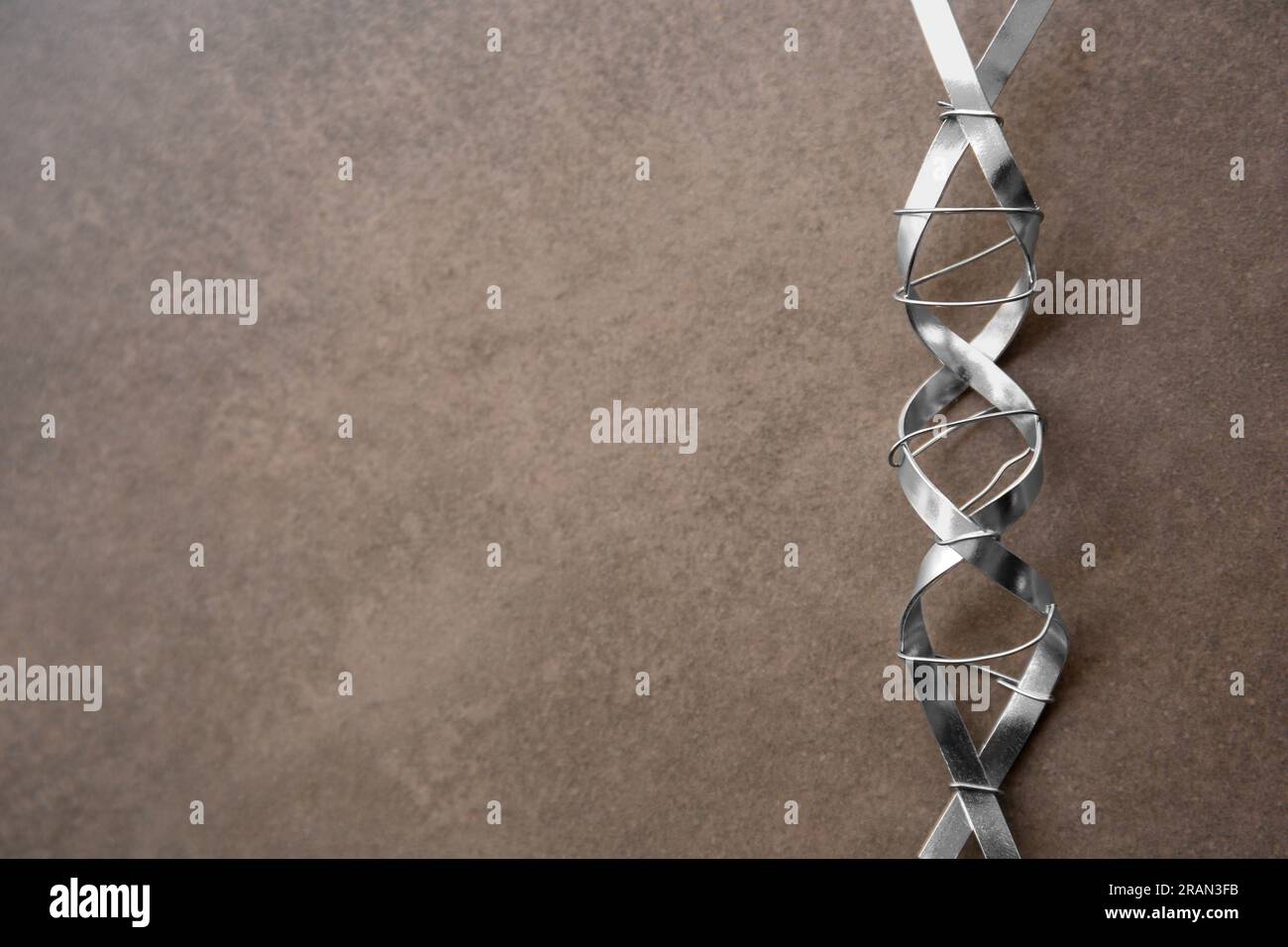 DNA molecule model made of metal on brown background, top view. Space ...