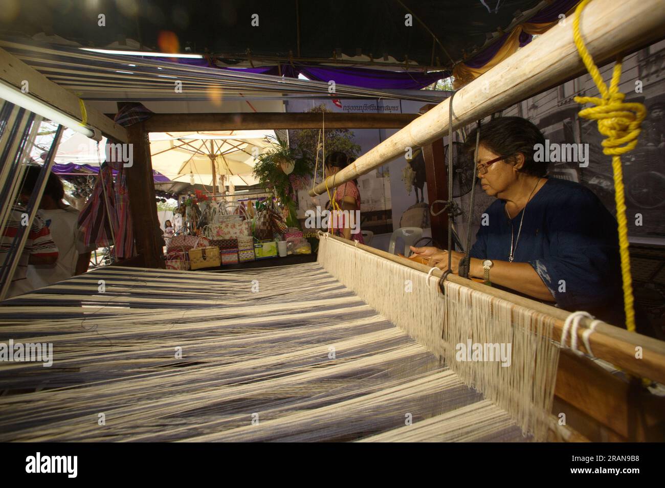 An unidentified elderly woman weaving large fabrics on an old loom for ...