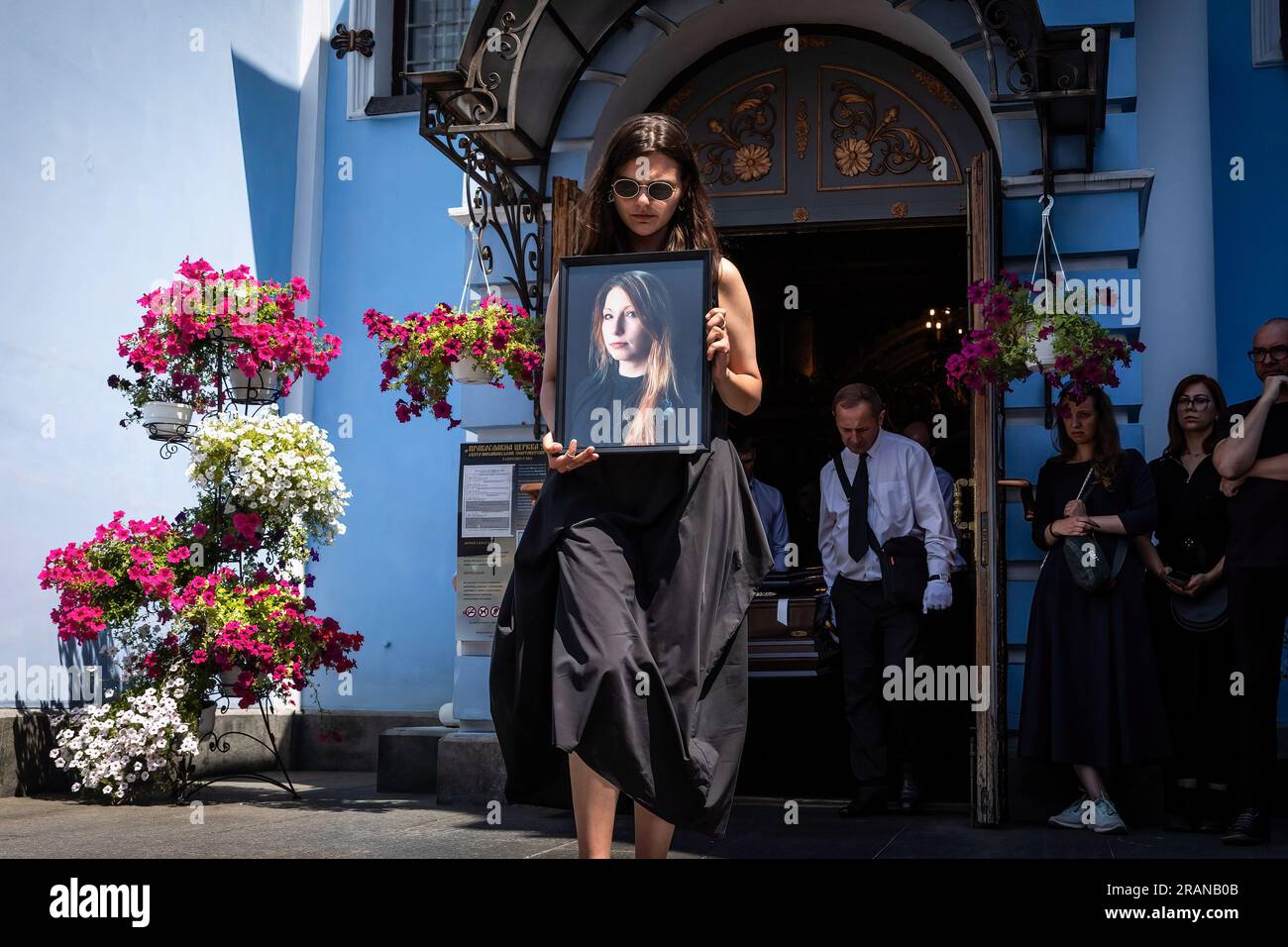 A woman holding a photo of Victoria Amelina walks out of St. Michael's ...