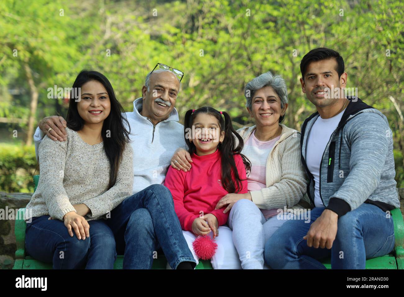 Happy family having good cheerful time sitting on bench in green park ...