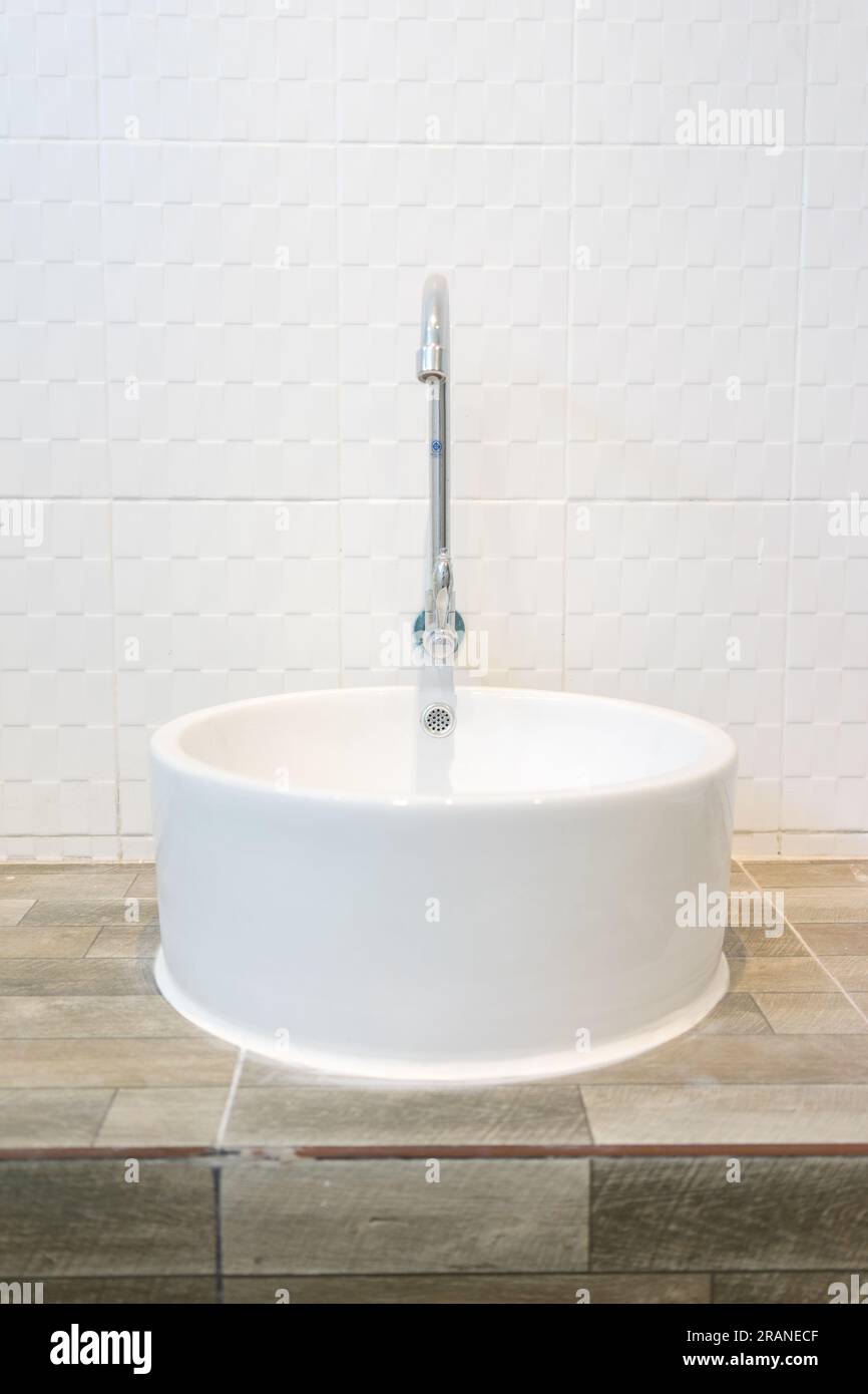 White sink and chrome faucet with white tiles wall and wood pattern ...