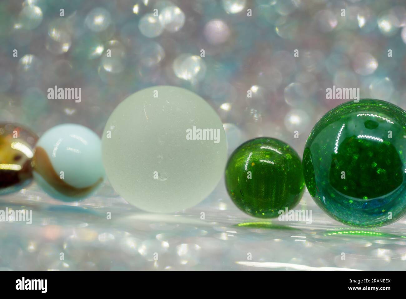 Glass balls and colorful marbles against a light blurred background ...