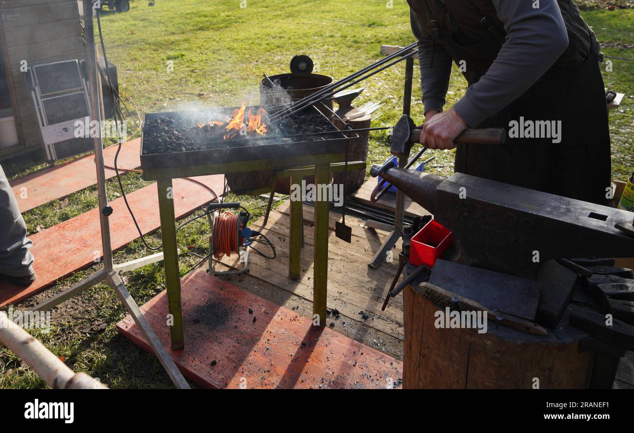 Blacksmith with red-hot iron and open charcoal fire at work Stock Photo ...