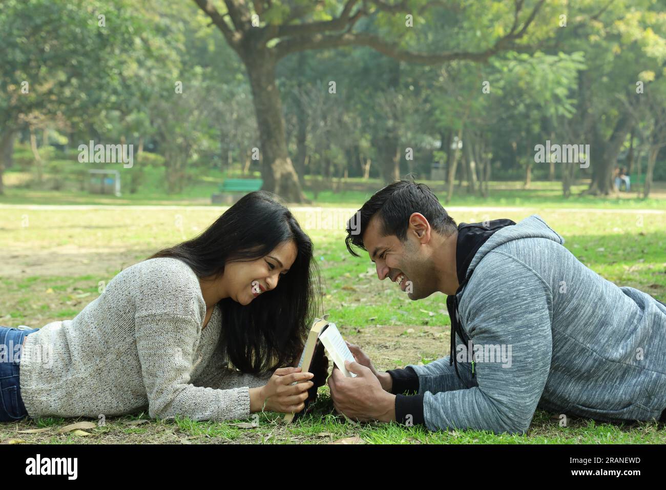 Beautiful Indian happy college students reading a book lying in the ...