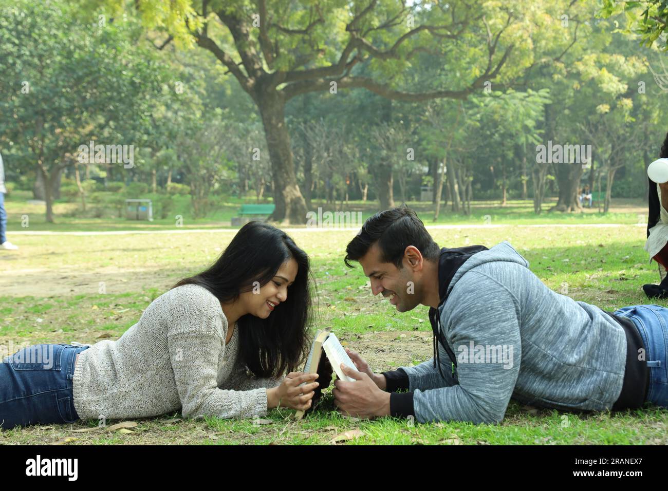 Beautiful Indian happy college students reading a book lying in the ...