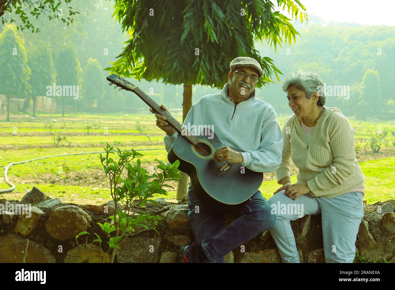 Happy Old Couple sitting together in green park. Grandpa performing ...