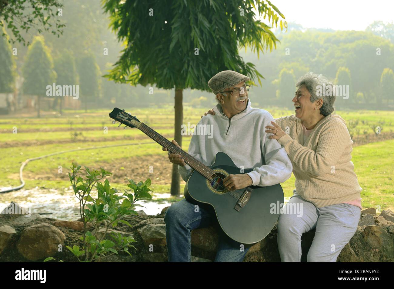 Happy Old Couple sitting together in green park. Grandpa performing ...