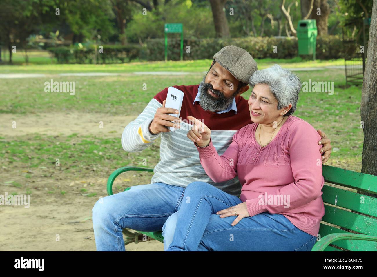 Old Age Couple Sitting On The Bench In A Lush Green Serene Environment
