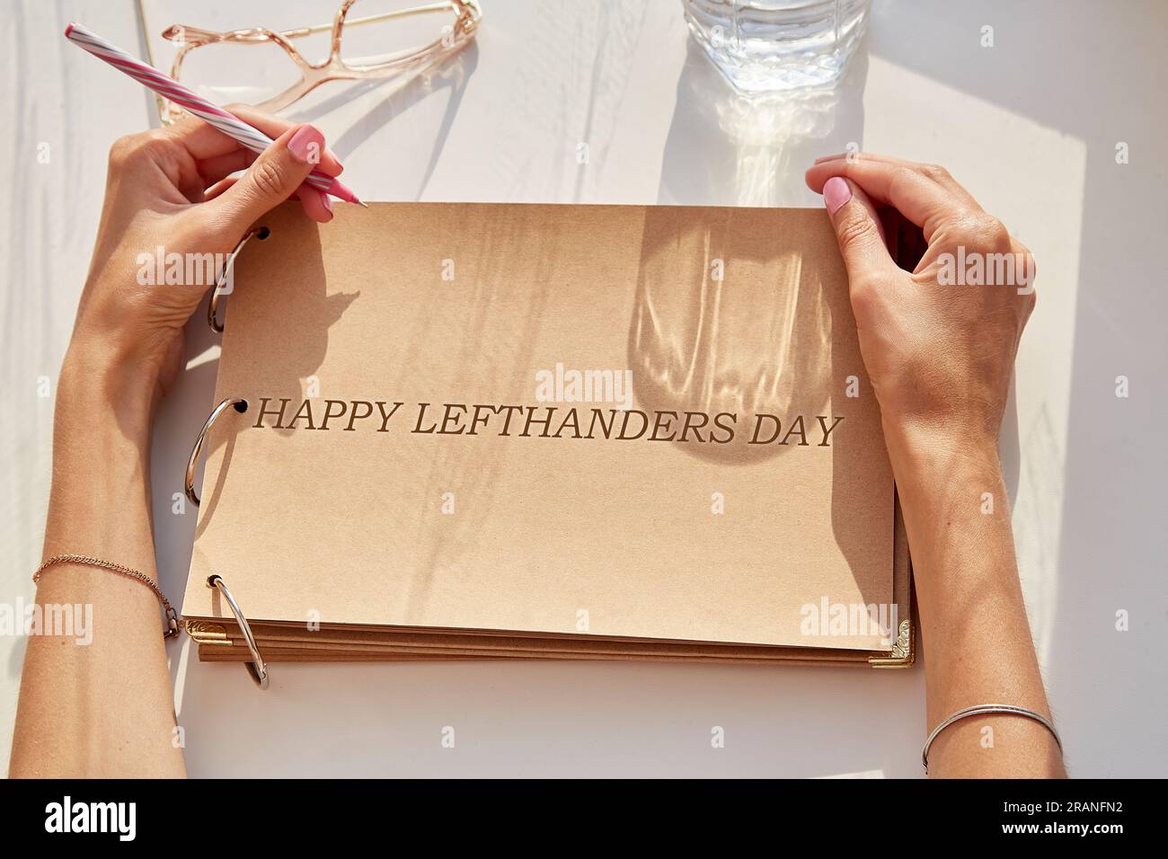 Woman holds a pen in her left hand, craft paper album. Text Happy Left ...