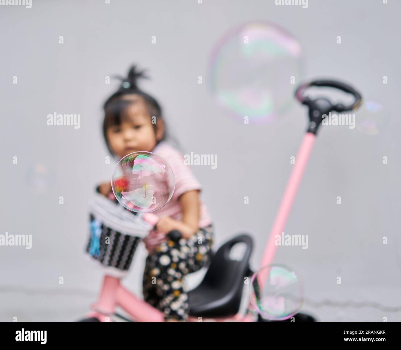 A bubble floating in front of a blurred toddler, on a bicycle, concept ...
