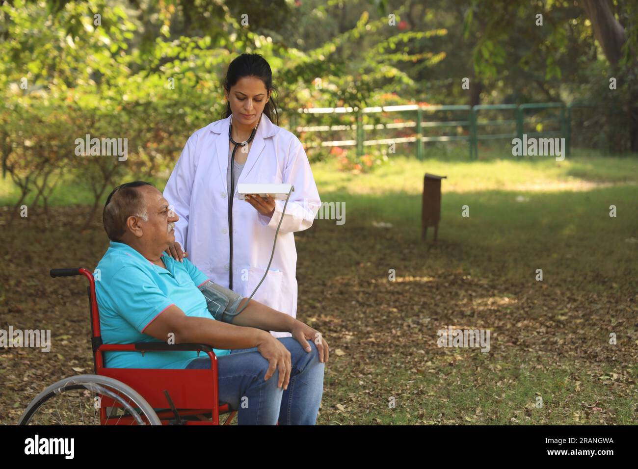 Doctor taking care of old patient in hospital garden. patient is ...