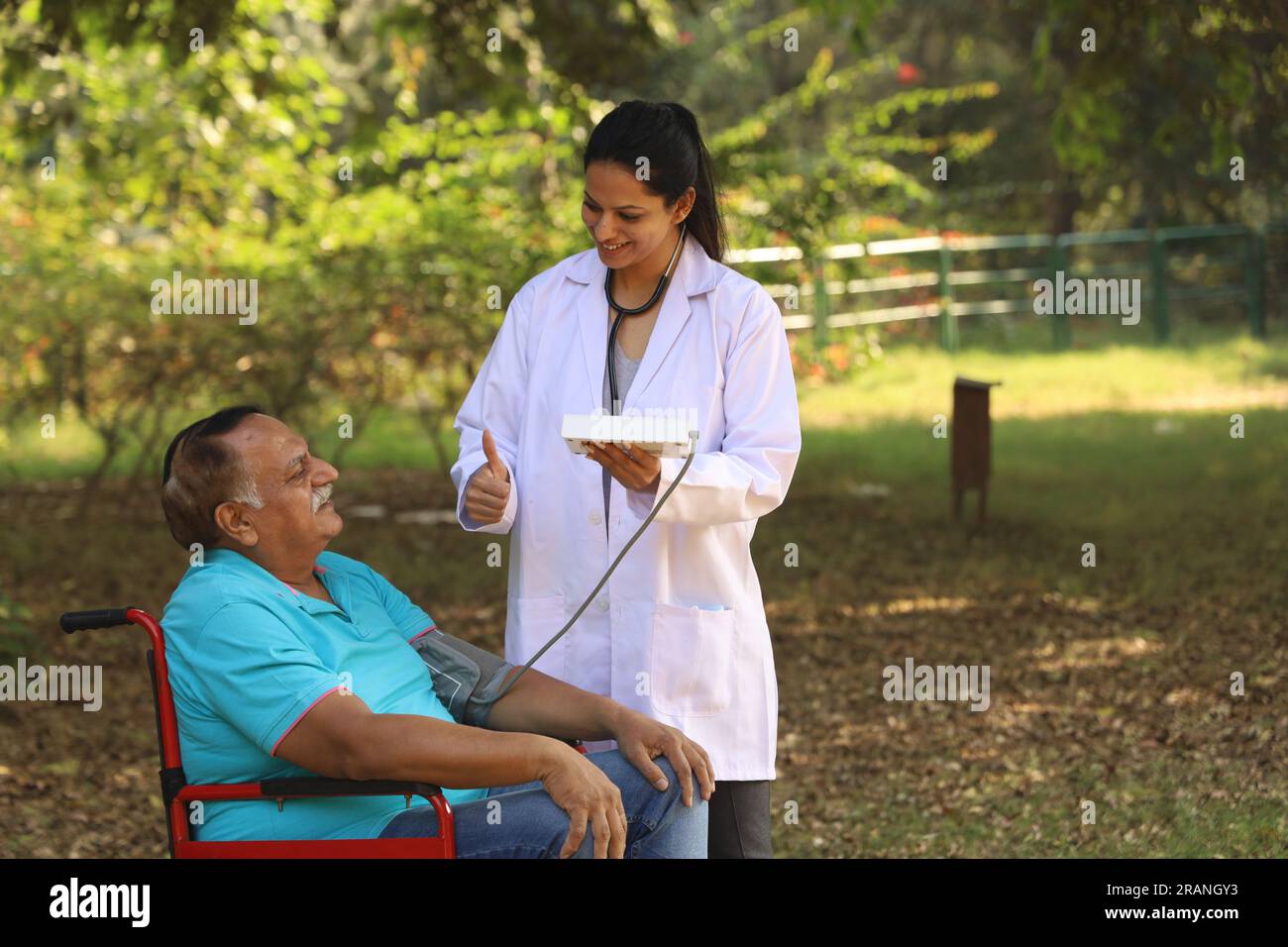 Doctor taking care of old patient in hospital garden. patient is ...