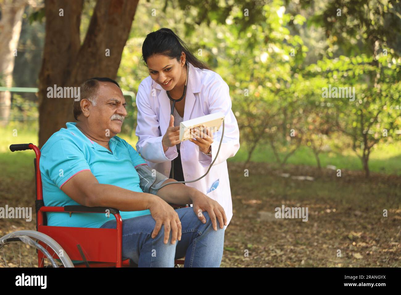 Doctor taking care of old patient in hospital garden. patient is ...