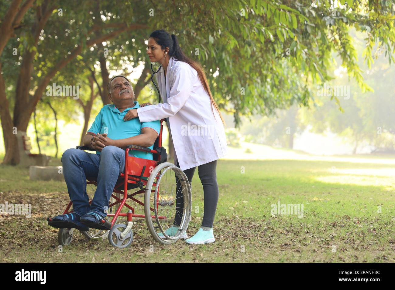 Doctor taking care of senior patient in hospital garden. The patient is ...